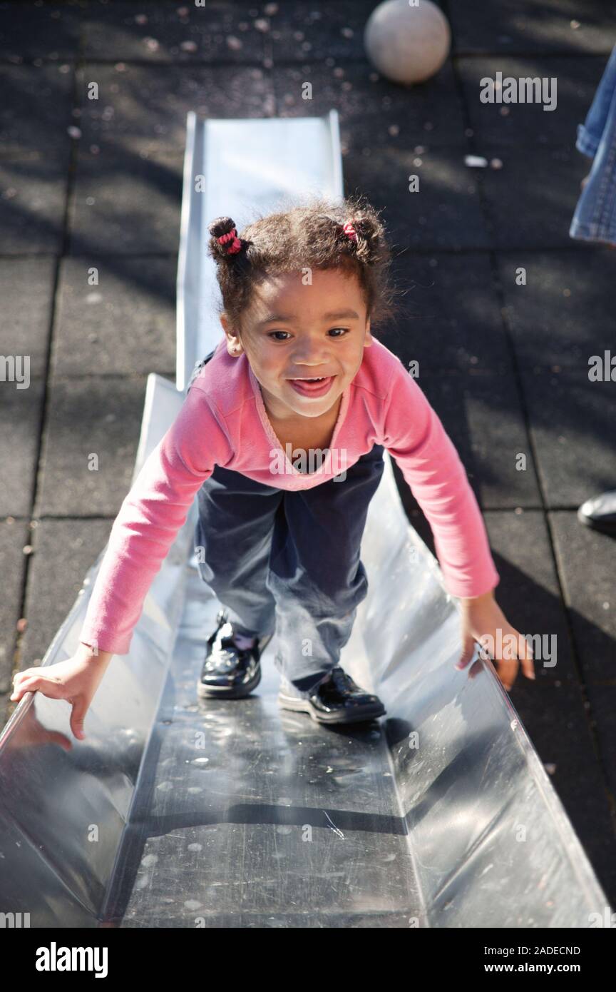 Young girl climbing up a slide in the playground Stock Photo - Alamy