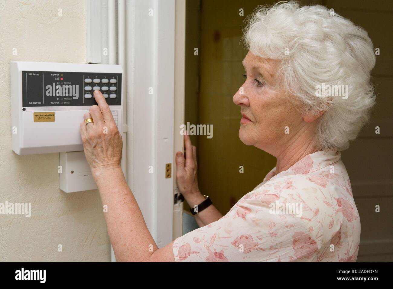 Woman setting house alarm system Stock Photo - Alamy