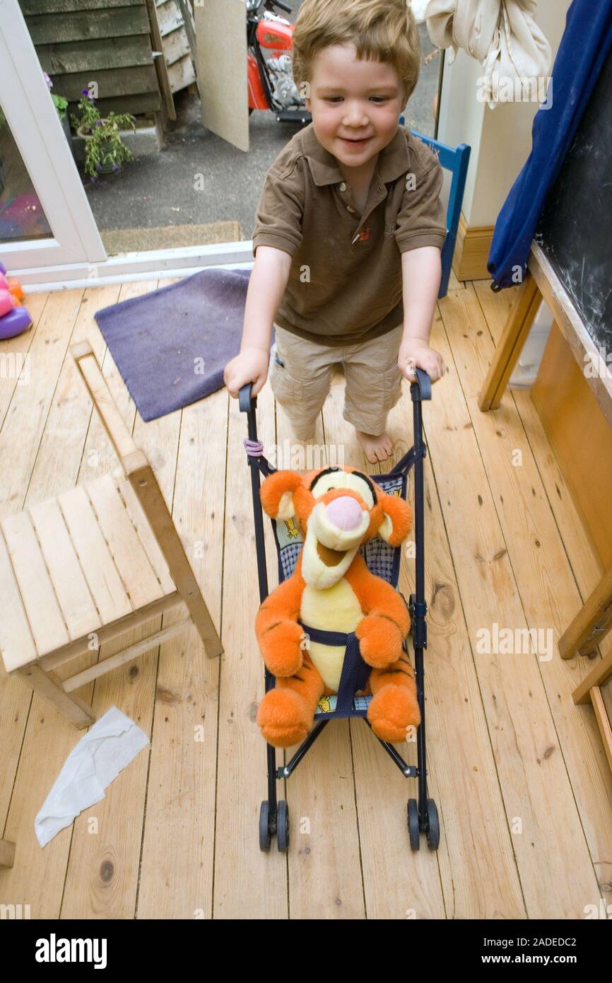 Little boy playing with his teddy in a pushchair Stock Photo - Alamy