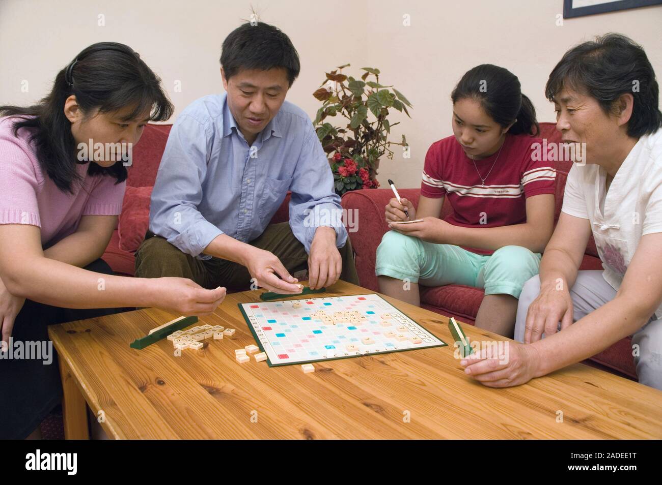 Three generations of family playing a game of scrabble together at home ...