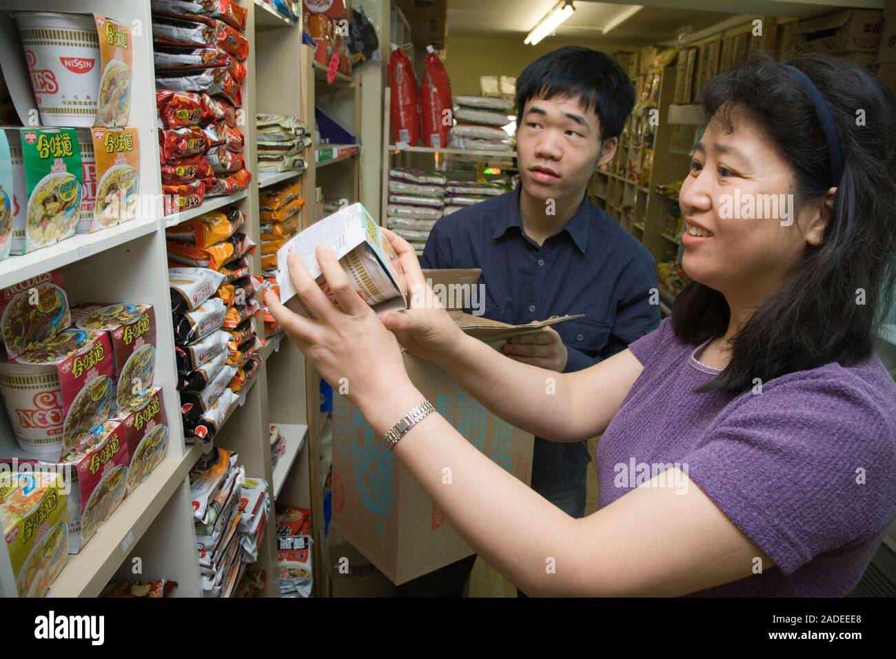 Shop workers stacking shelves an oriental food stall Stock Photo - Alamy