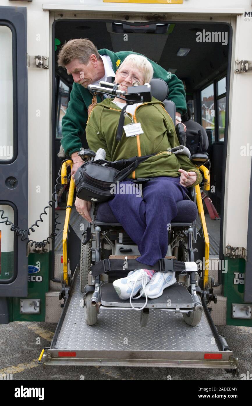 Driver helping wheelchair user up ramp into minibus Stock Photo - Alamy