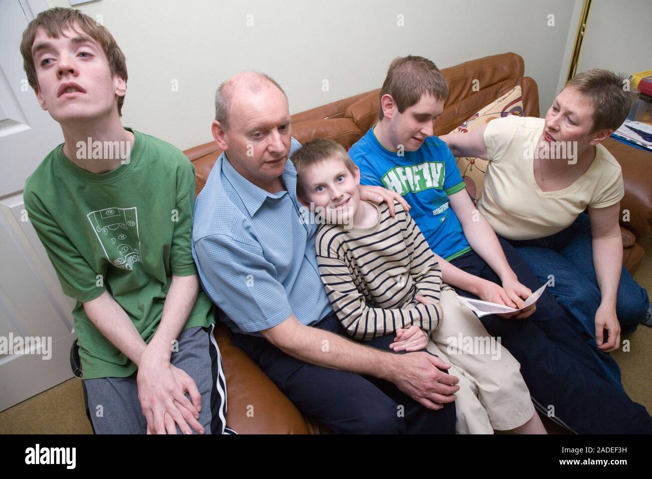 Mother and father relaxing at home with their three sons who have ...
