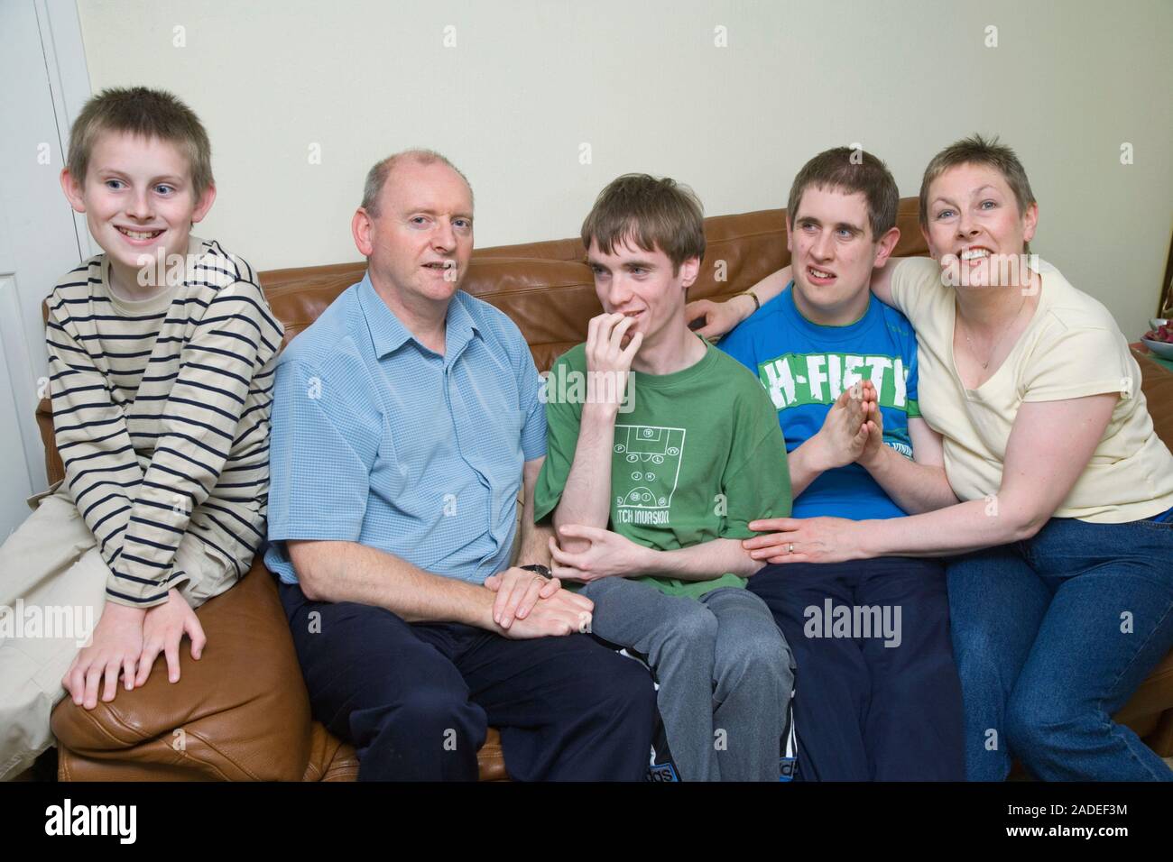Mother and father relaxing at home with their three sons who have ...