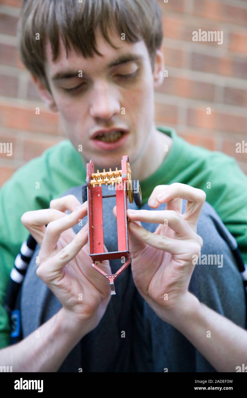 Teenage boy with autism playing with toy plough Stock Photo - Alamy