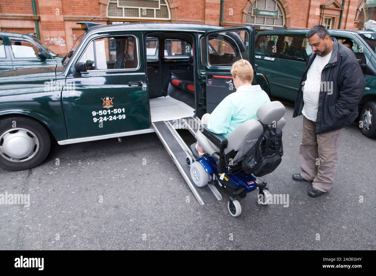 Woman wheelchair user accessing taxi via ramps Stock Photo - Alamy