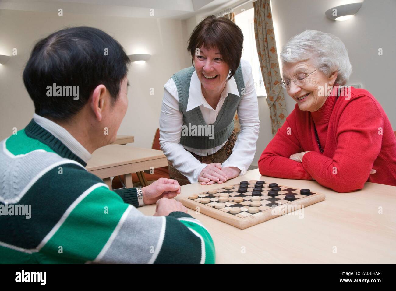 Group of older people playing draughts in a care home Stock Photo - Alamy