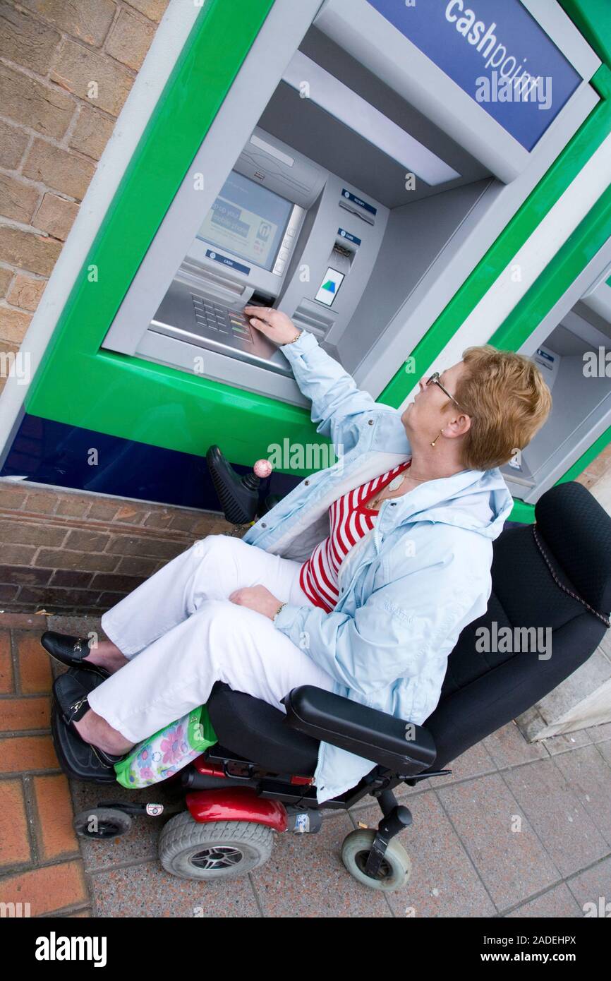 Older woman wheelchair user using a cashpoint machine Stock Photo - Alamy