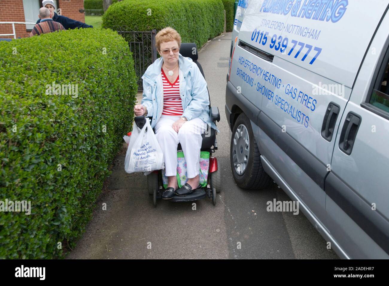 Older woman wheelchair user trying to get past a van parked ...