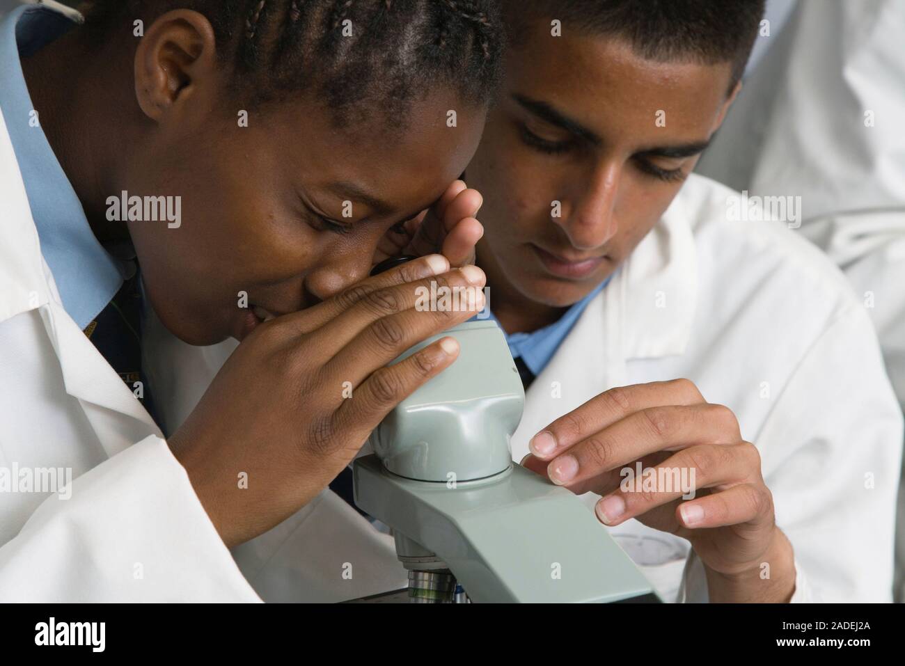 Secondary school students looking through a microscope in a science ...