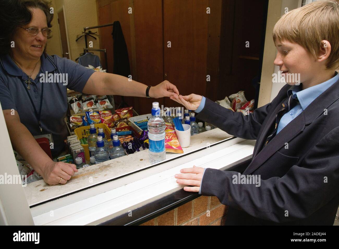 Secondary school student buying a bottle of water from the school tuck ...
