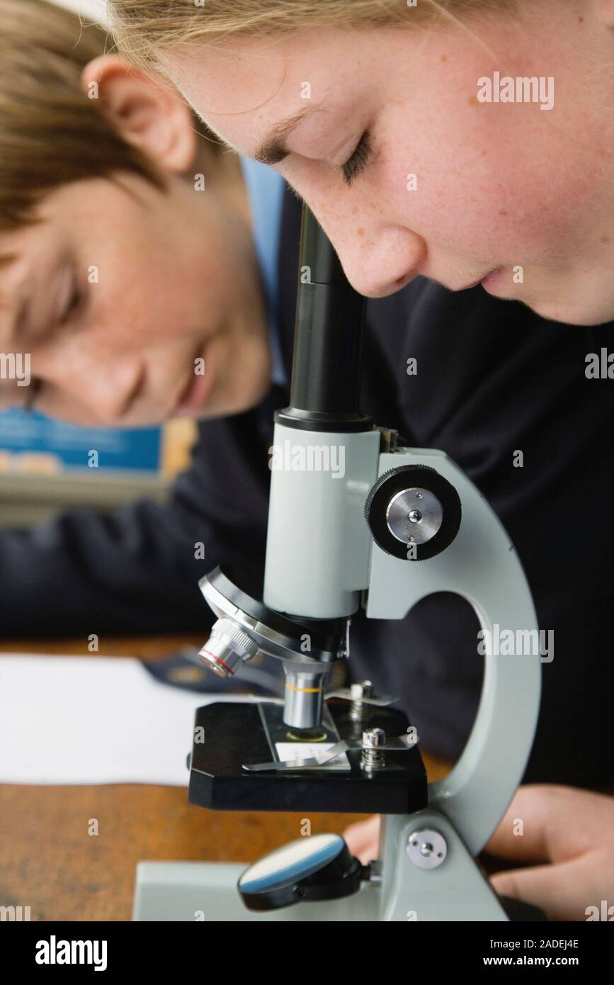 Secondary school student looking through a microscope in a science ...