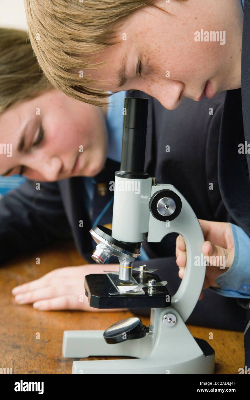 Secondary school student looking through a microscope in a science ...