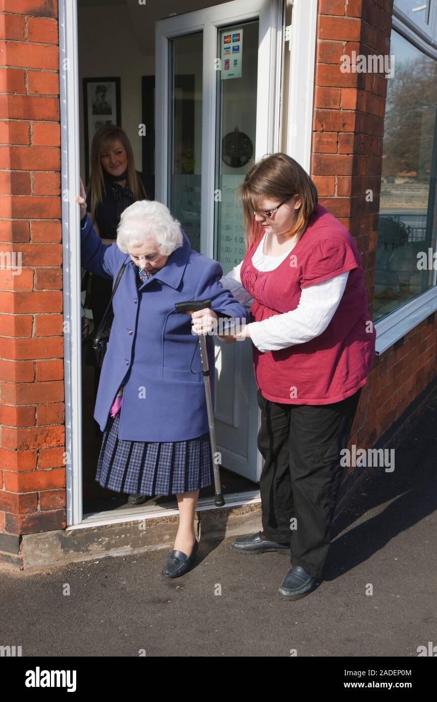 Carer helping old woman down step Stock Photo - Alamy