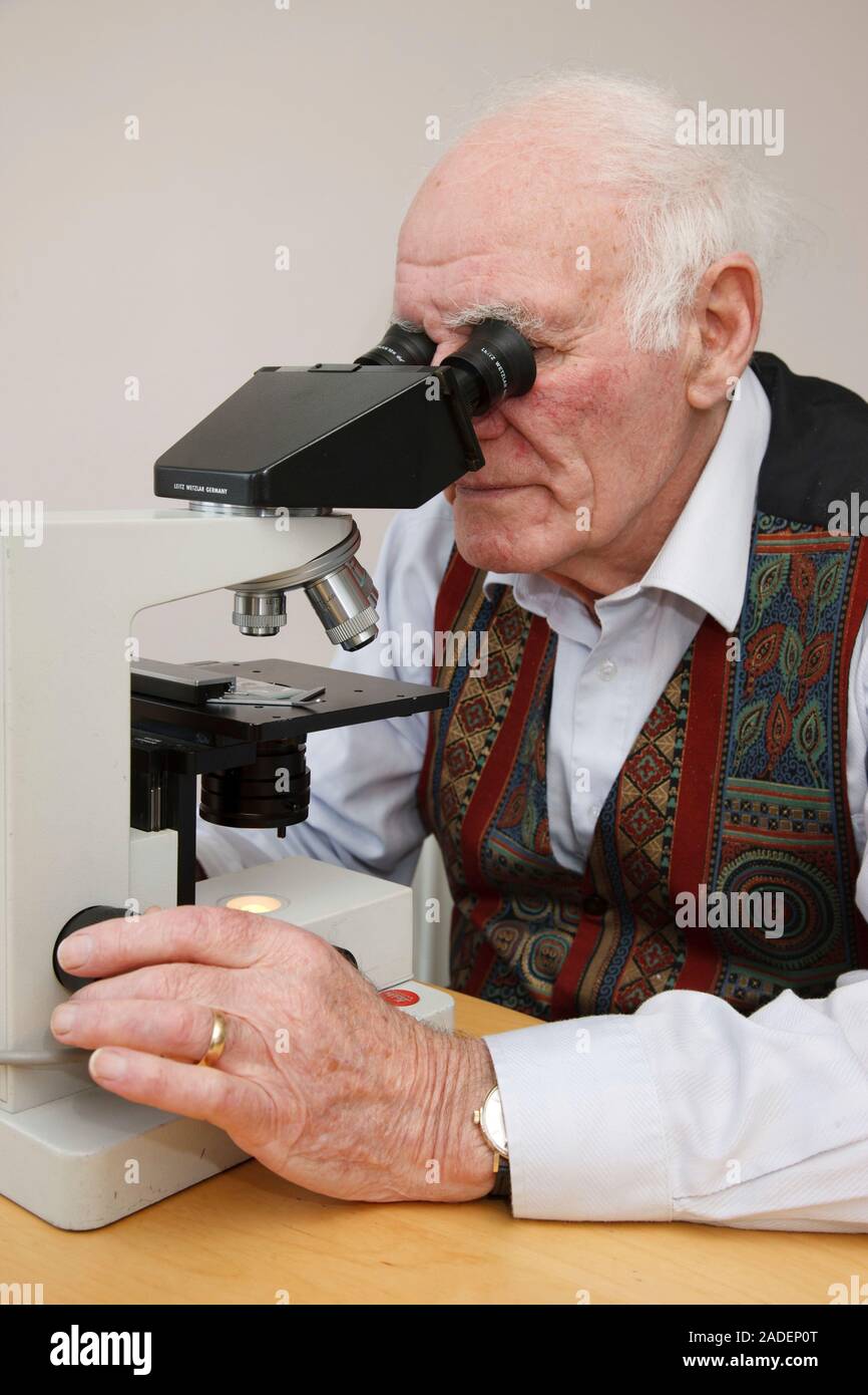 Elderly man looking through microscope Stock Photo - Alamy