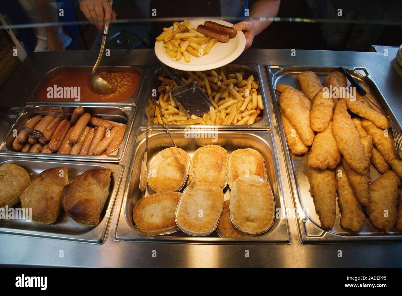 Dinner lady serving up a meal from trays in the school canteen Stock ...