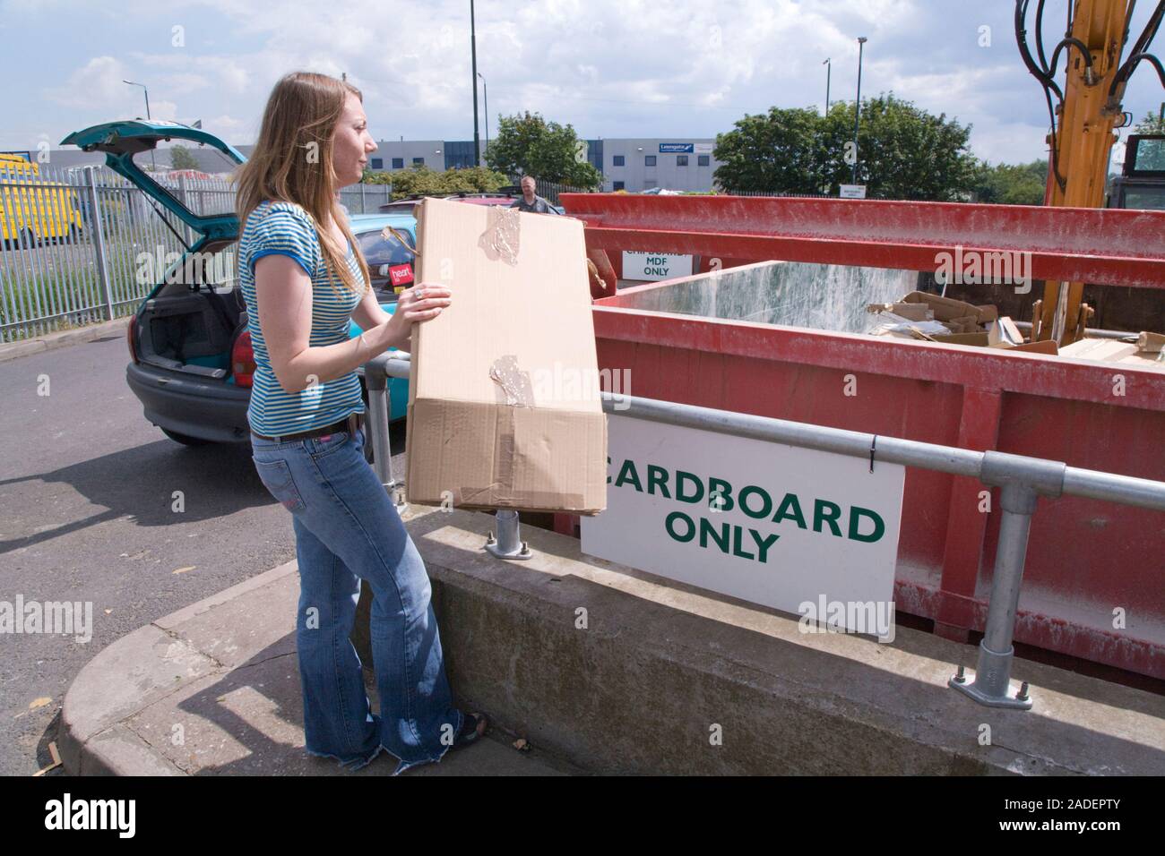 Woman recycling cardboard into a skip at the city tip Stock Photo - Alamy
