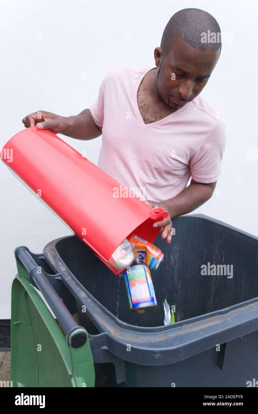 Man putting tins and cans into recycling wheelie bin ready for ...