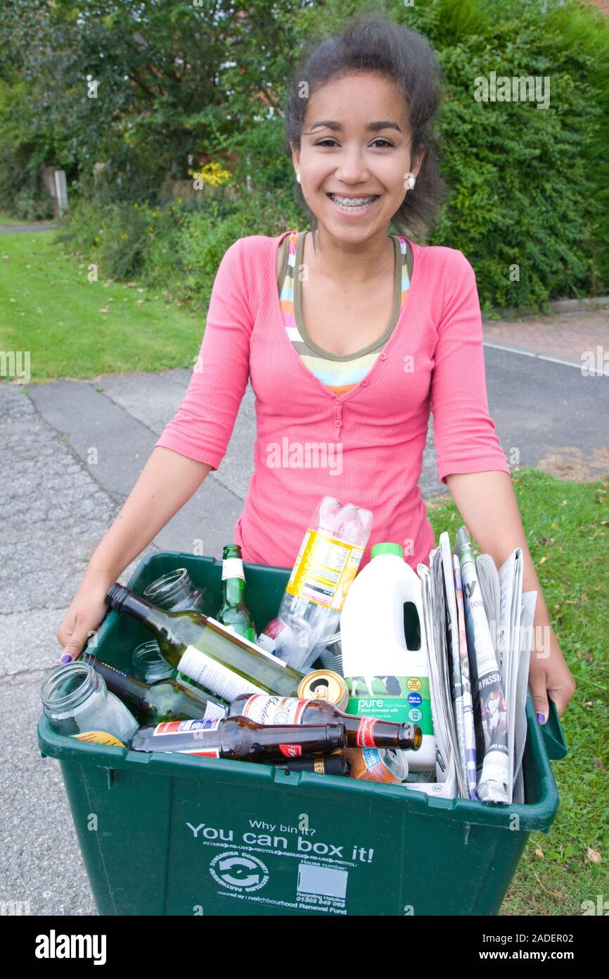 Teenage girl carrying curb side recycling collection box out onto the ...