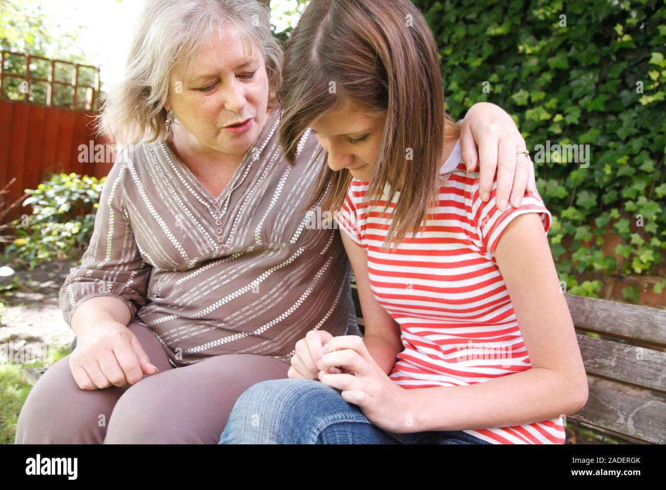 Woman and teenage girl talking on bench Stock Photo - Alamy