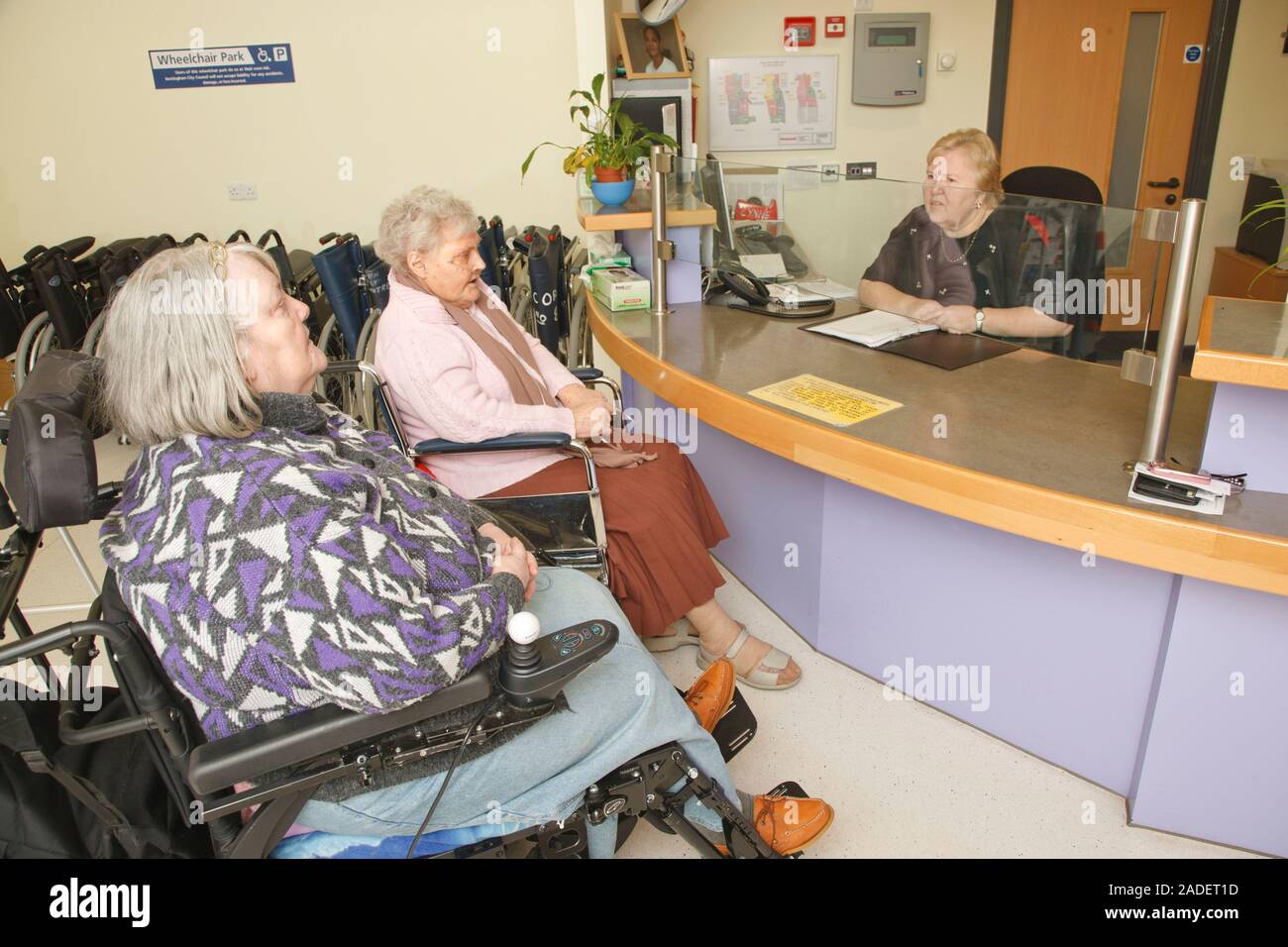 Receptionist with wheelchair users at reception for a resource for ...