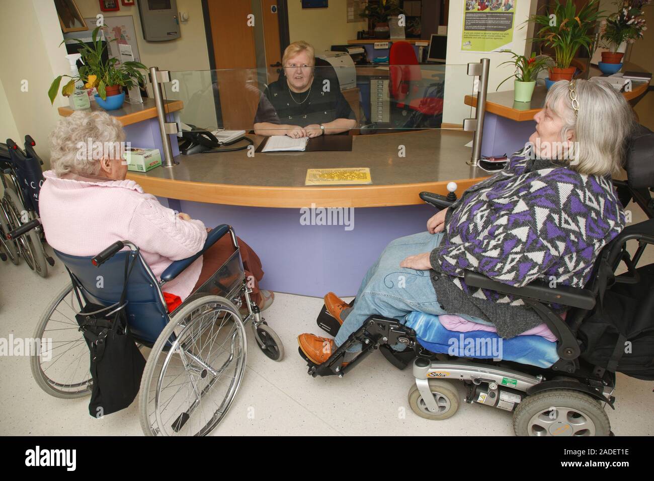 Receptionist with wheelchair users at reception for a resource for ...