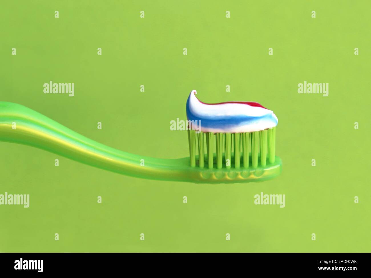 close-up of a green toothbrush with striped toothpaste in front of a ...