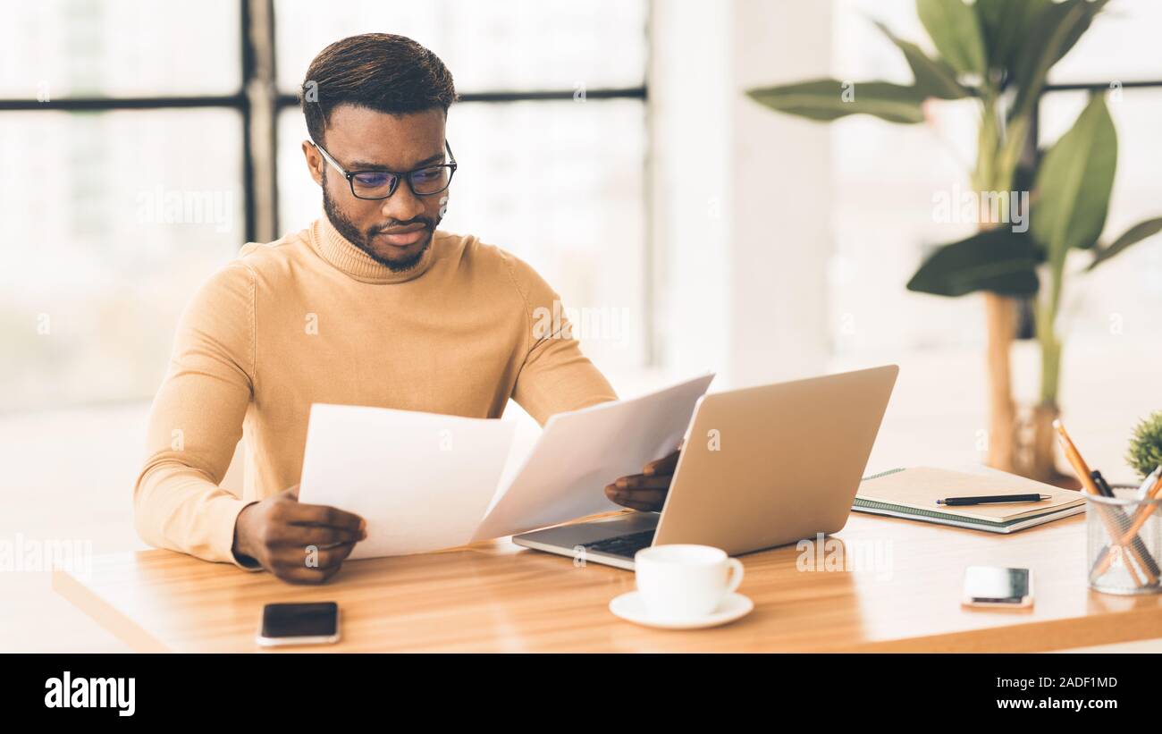 African american manager checking reports in modern office Stock Photo ...