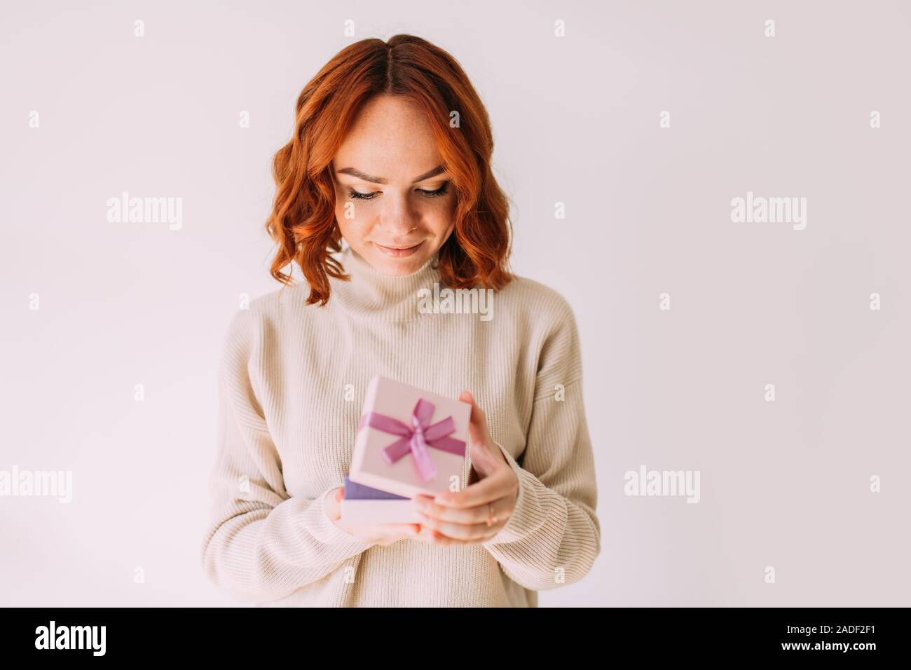 Young girl with festive mood gently smiles, holding a pastel coloured ...