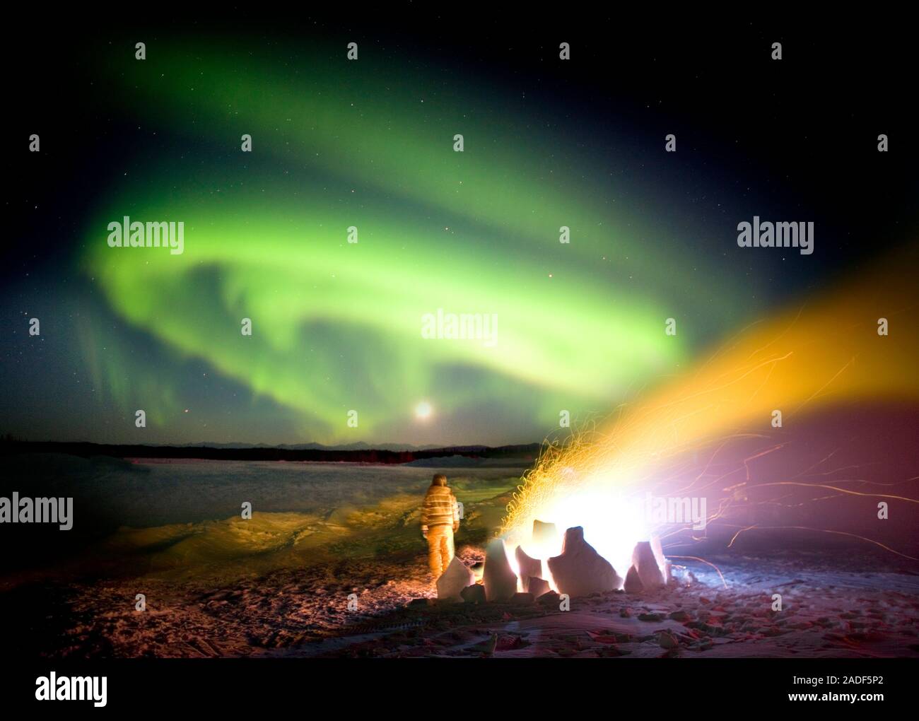 Aurora watching. Time-exposure image of an aurora watcher by a fire ...