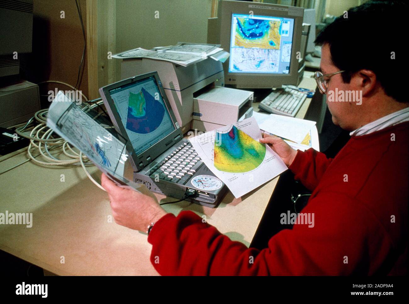 Storm research. Scientist studies weather maps whilst planning an ...