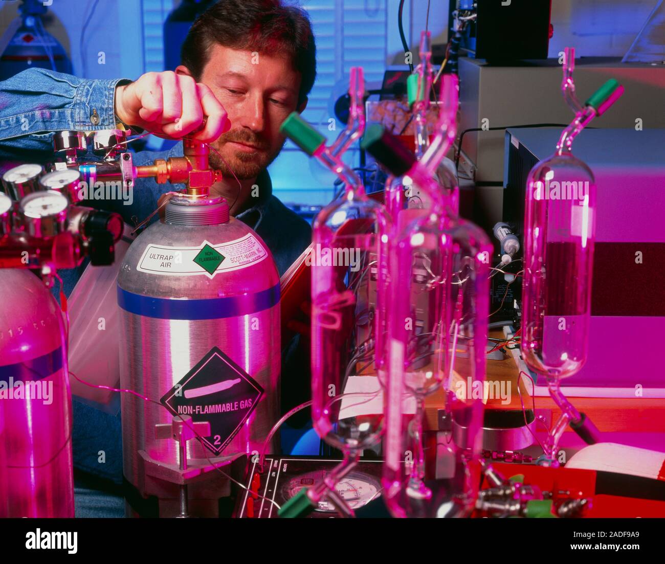Air analysis. Scientist with a gas cylinder containing a pressurised ...