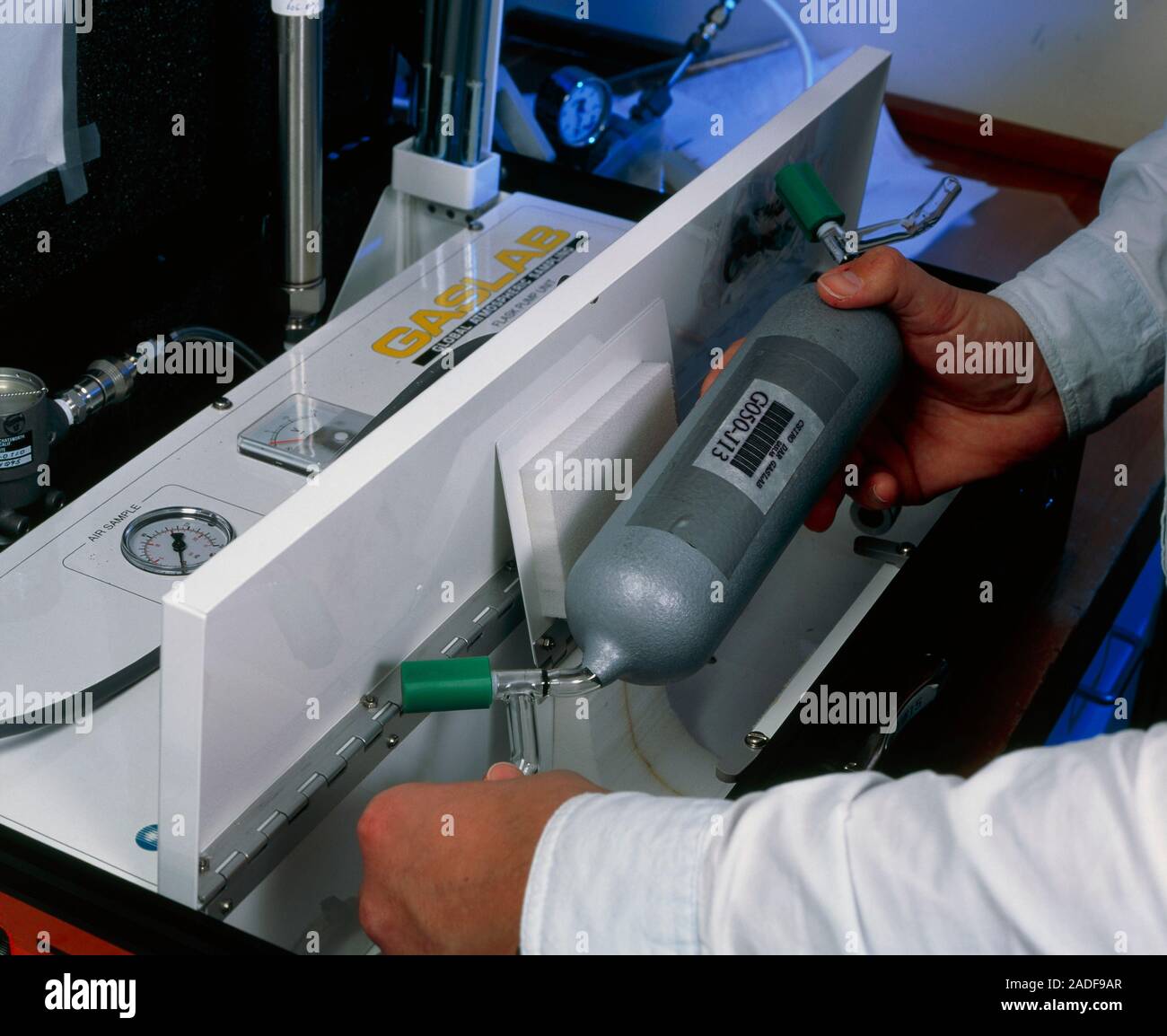 Air analysis. Technician fills a gas cylinder with a sample of air for ...