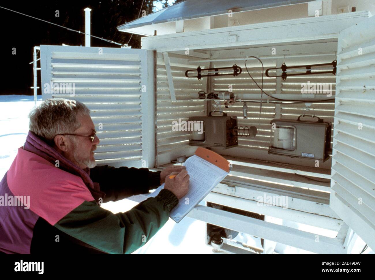 Weather research. Researcher reading instruments at a weather station ...