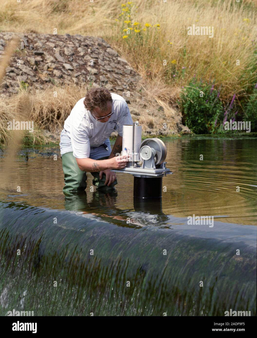 Water level recorder in a river, being adjusted by a scientist. It uses ...