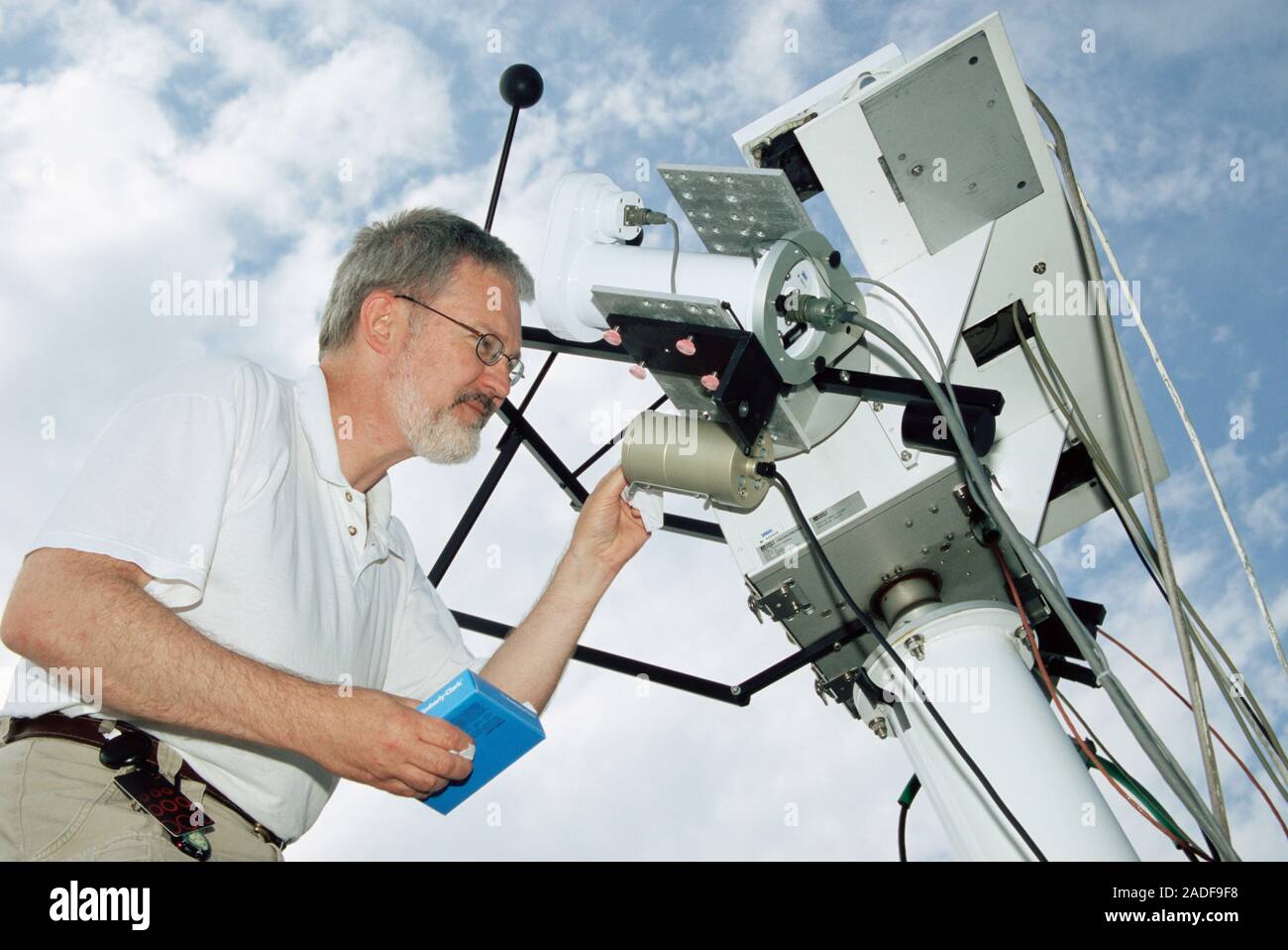 Sunshine detector. Meteorologist cleaning a sunshine detector mounted ...