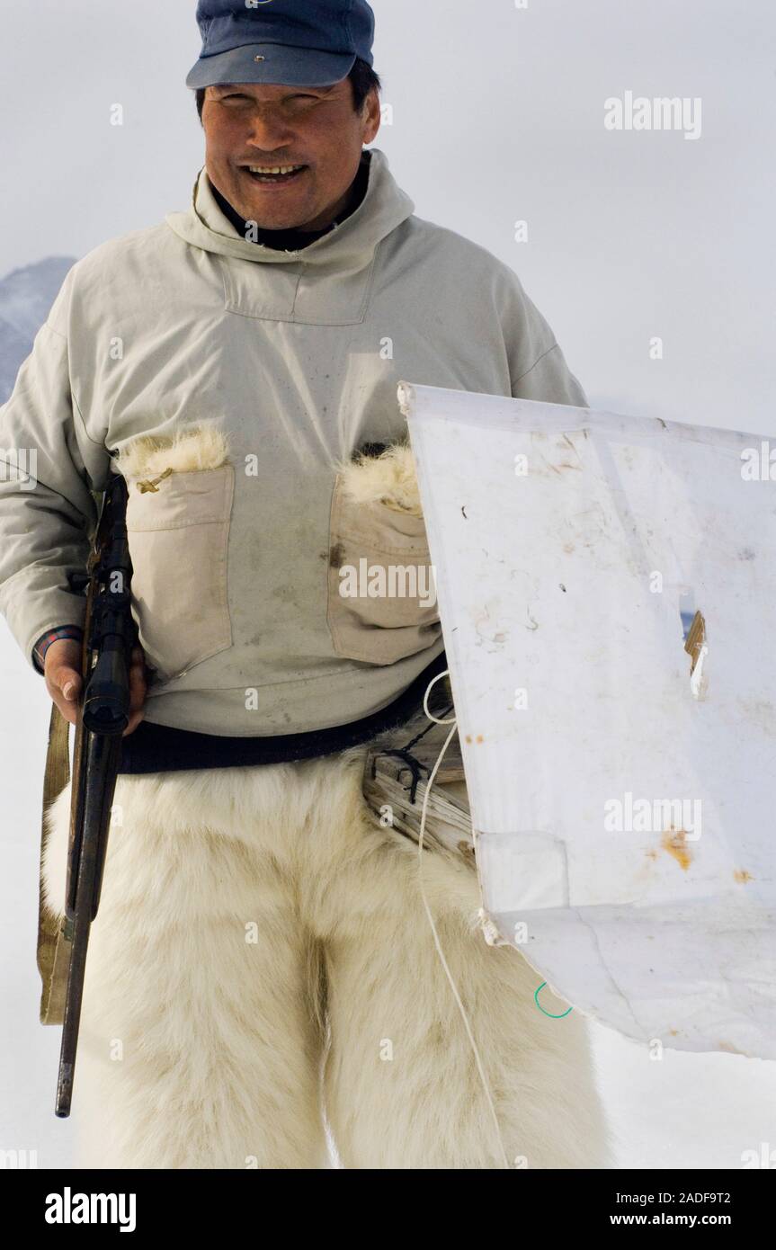 Inuit hunter. Inuit hunter holding a rifle and white blind. He is ...