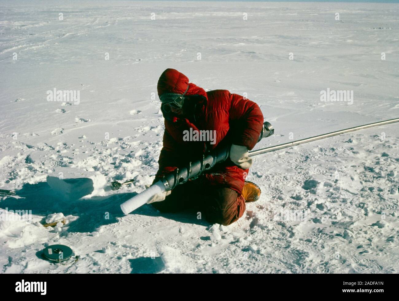A glaciologist in Antarctica extracts an ice core from the apparatus ...