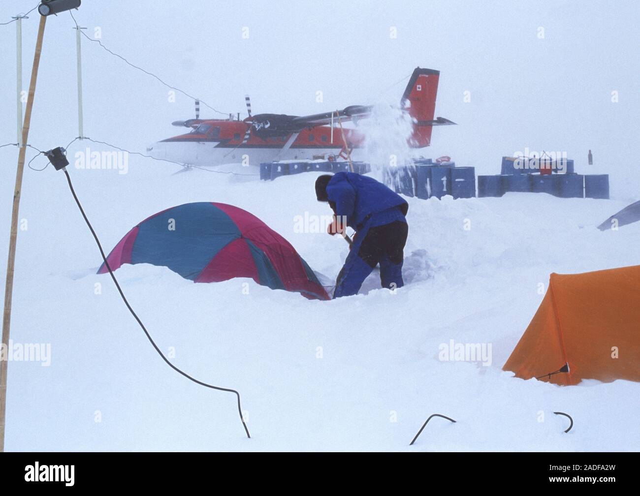 Snowbound field station. Researcher clearing snow from around a ...