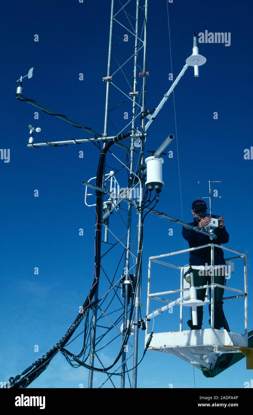 Antarctic research. Researcher adjusting a weather mast used to monitor ...