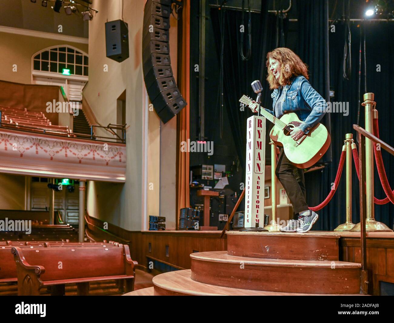 Tourist poses on the stage of legendary Ryman Auditorium. The Ryman ...