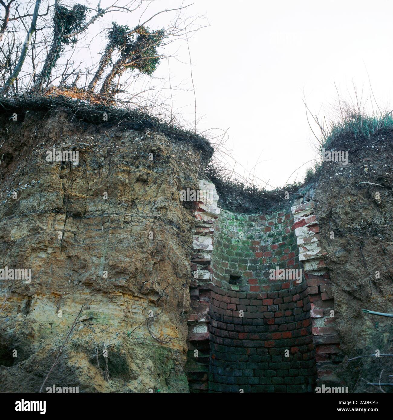Cliff erosion. The erosion has cut through an old brick well shaft ...