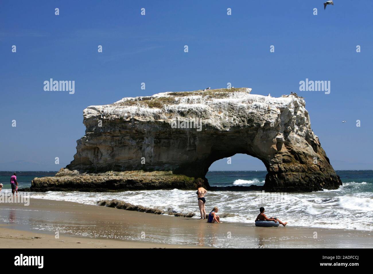 Sea arch protruding from a beach. This natural bridge was formed by ...