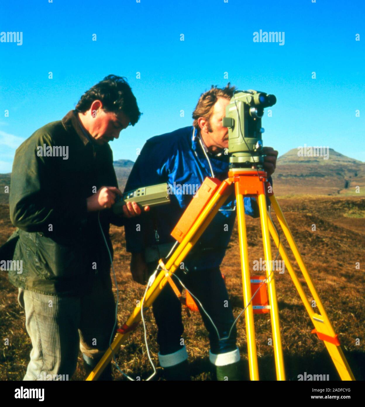 Geologists using a theodolite, a surveying instrument for measuring ...