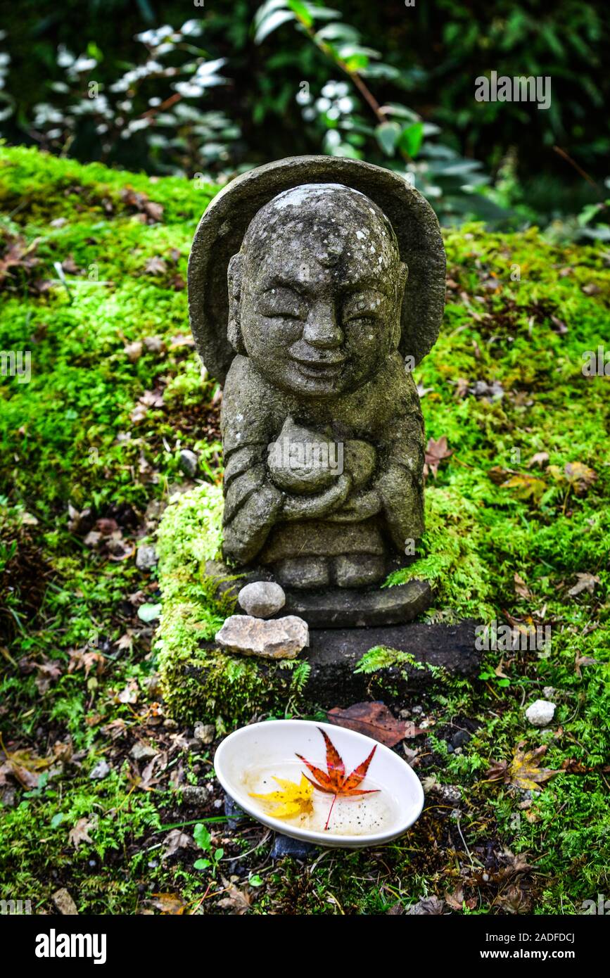 Stone statues of smiling Jizo Bosatsu with green moss at zen garden in ...