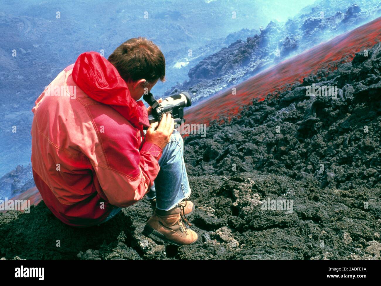 Volcanologist with a camcorder by a lava flow on the volcano Mount Etna ...