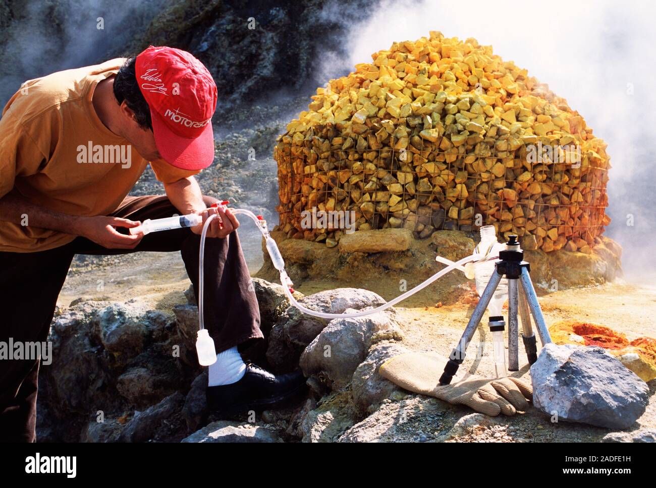 Sampling volcanic gas. Vulcanologist taking a sample of gas emitted by ...