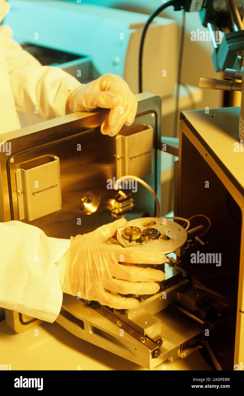 Volcanic rock analysis. Technician placing a sample of basalt rock from ...