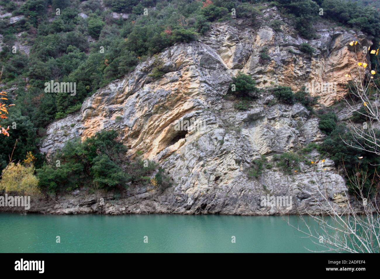 Folded rock strata by a lake. The strata were originally horizontal and ...