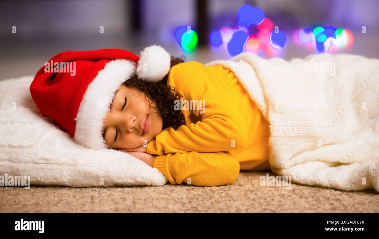 Little afro girl in Santa hat napping on floor Stock Photo - Alamy